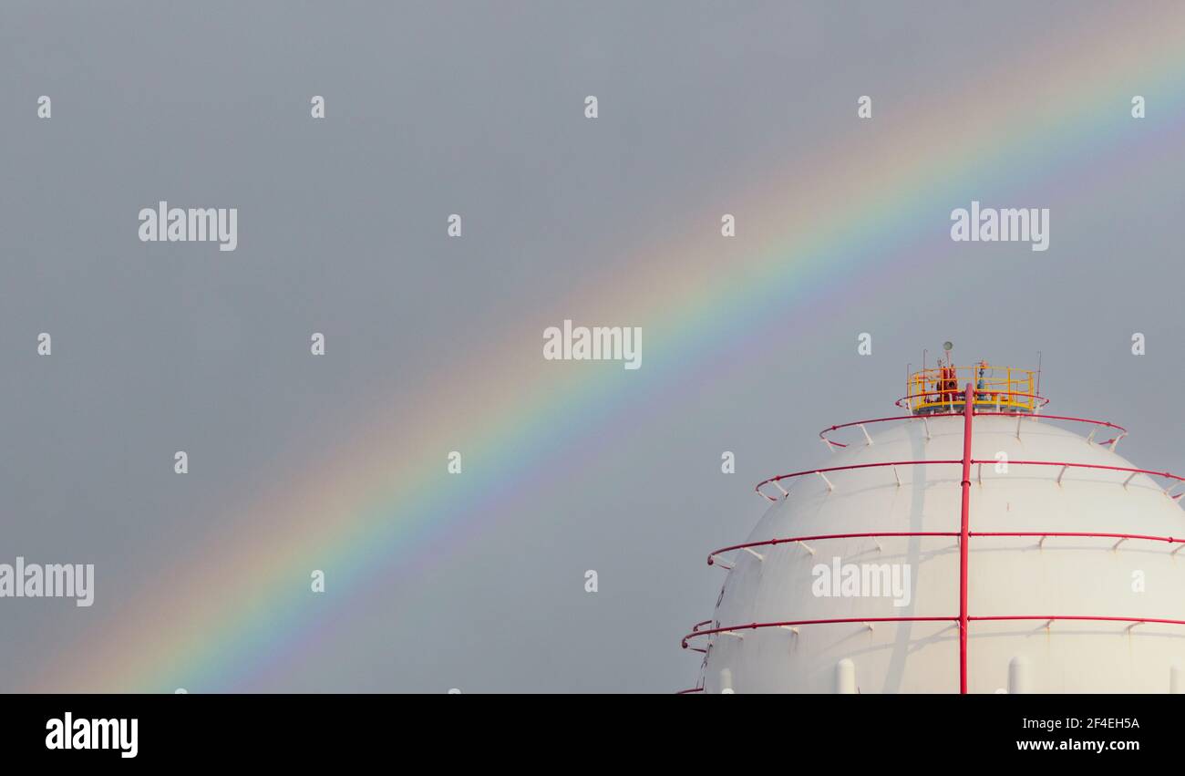 Industrial gas storage tank with rainbow sky background. LNG or ...