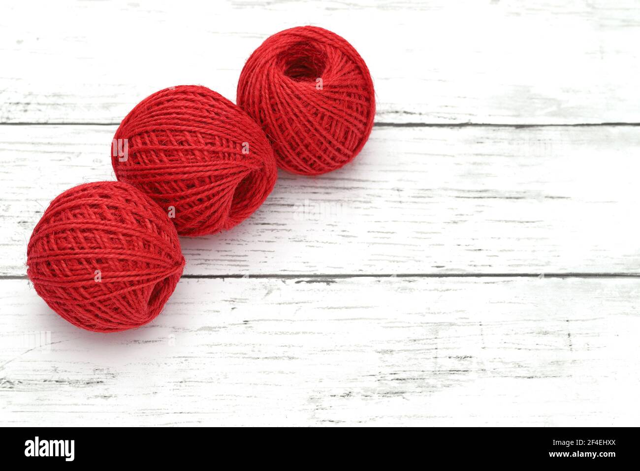 Ball of red threads on white wooden table Stock Photo - Alamy