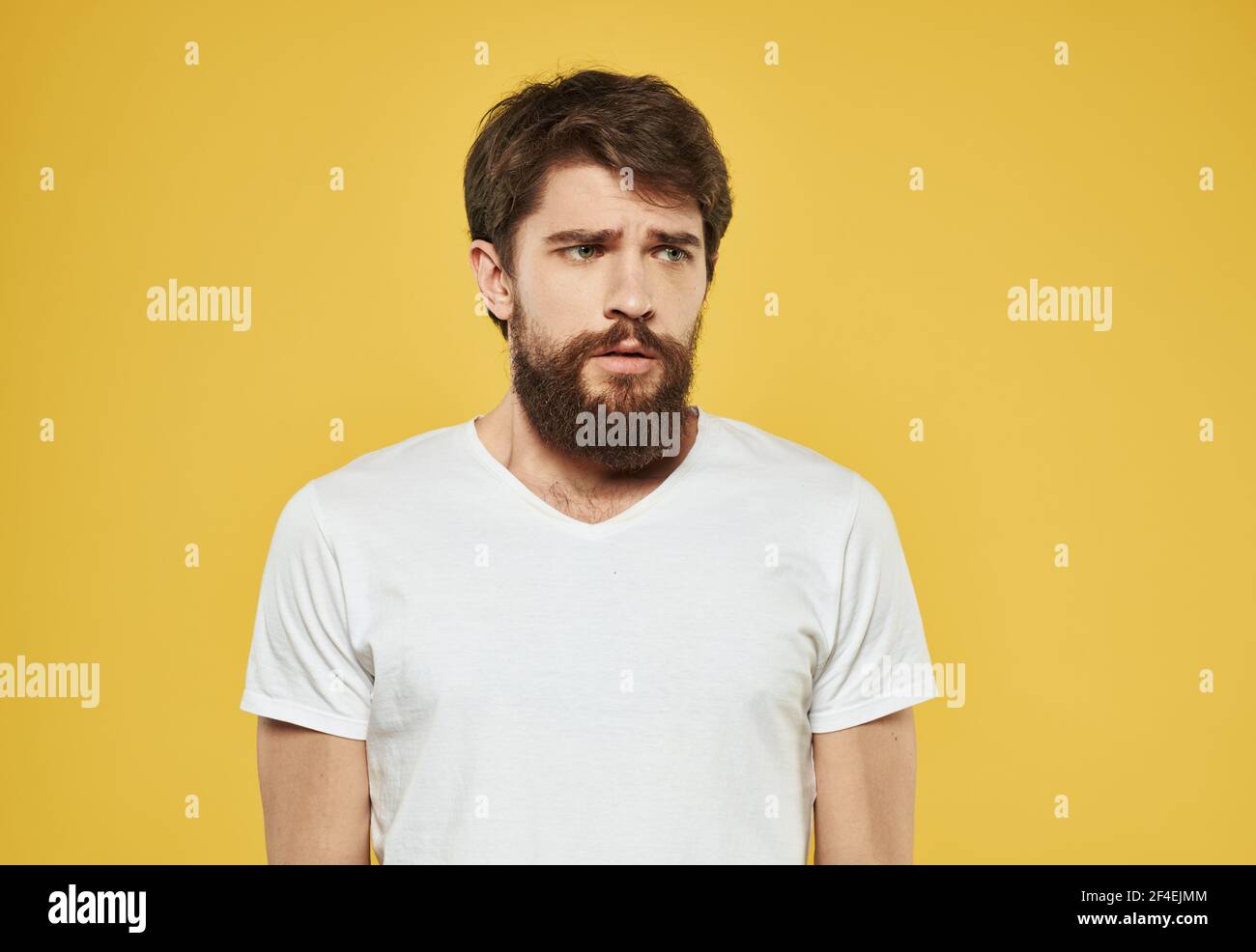 Portrait of a sad man on a yellow background cropped view of a white t ...