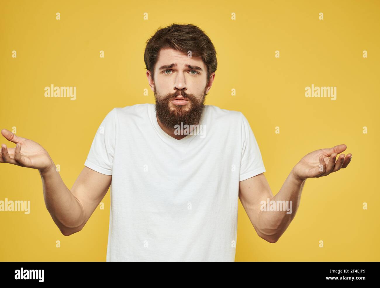 Puzzled look man gesturing with his hands on a yellow background ...