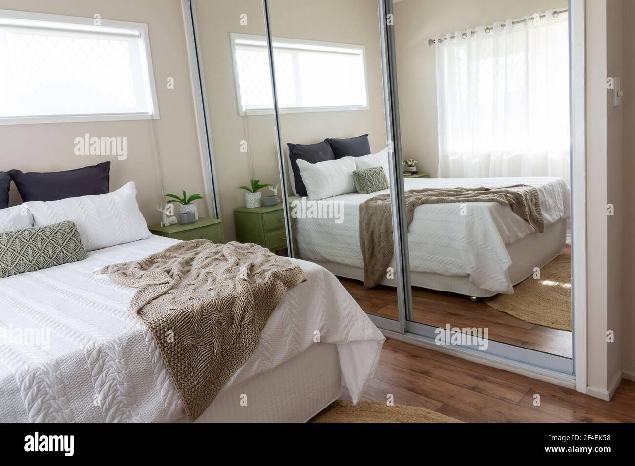 Light and airy modern bedroom interior with reflections in the mirror ...