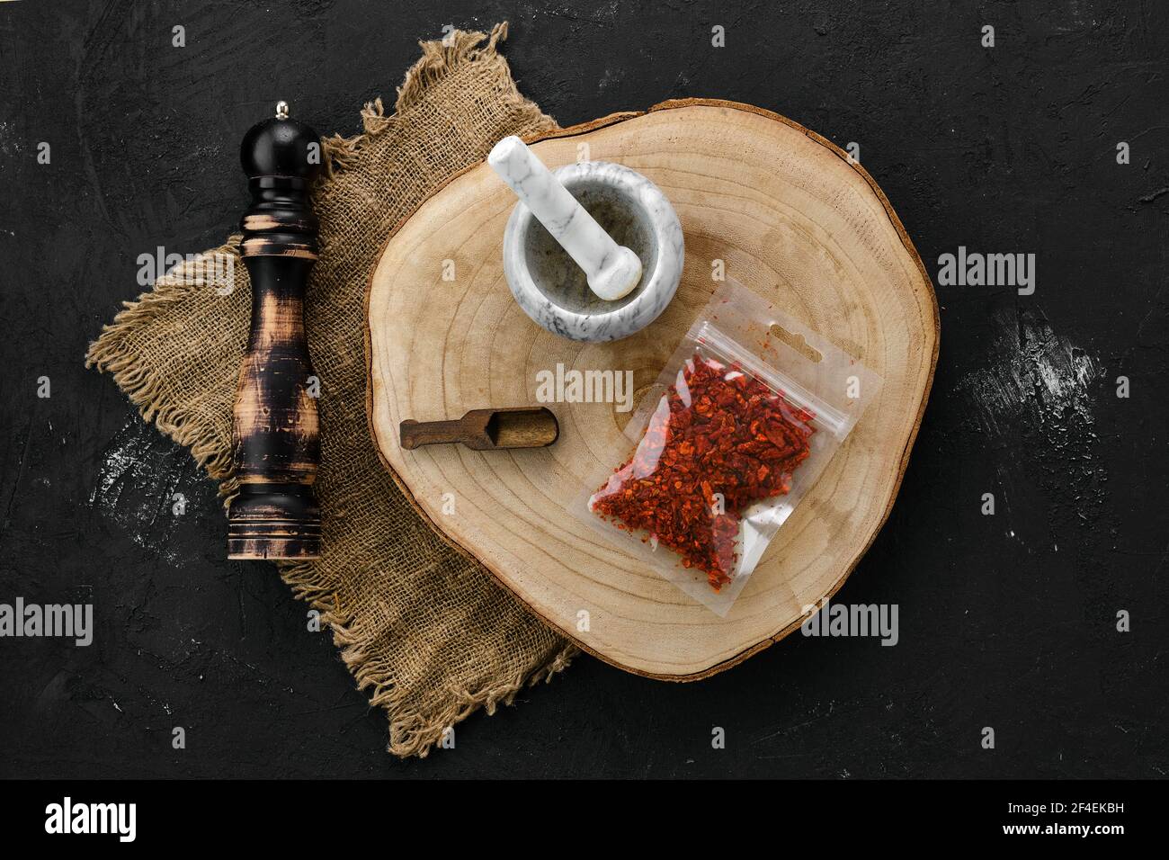 Wooden cross section with crushed paprika in plastic package and stone ...