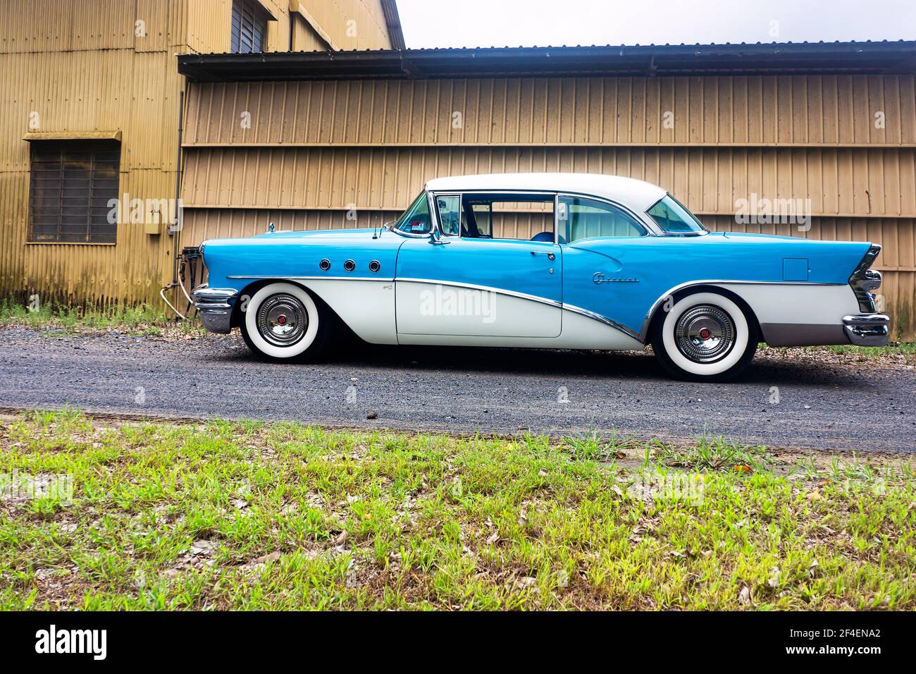 Side on view of a restored classic blue 1955 Buick sedan car against an ...