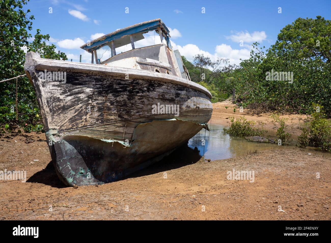 Derelict old pleasure boat with flaking paint and rusted hull left to ...