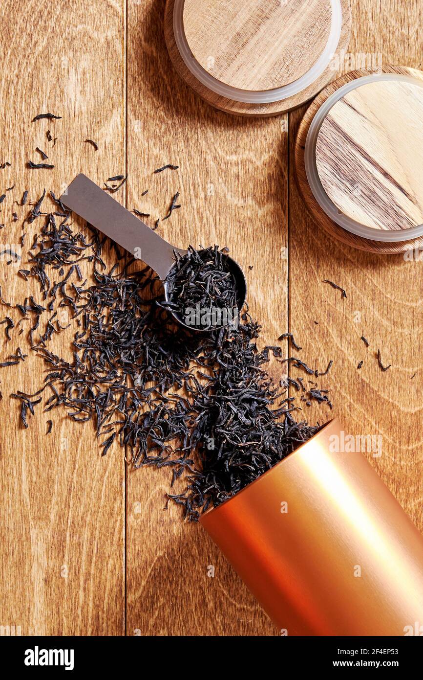 Black tea leaves scattered on the wooden table with cup holders and ...