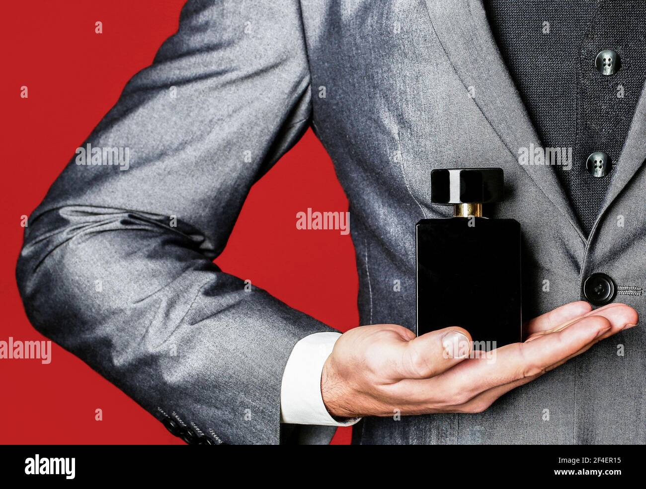 Man holding up bottle of perfume. Men perfume in the hand on suit ...
