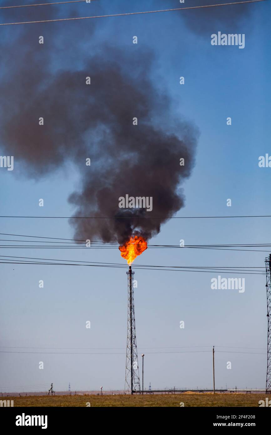 Burning nature gas torch of oil refinery plant in a desert against blue ...