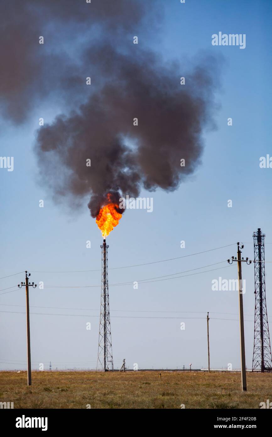 Burning nature gas torch of oil refinery plant in a desert against blue ...