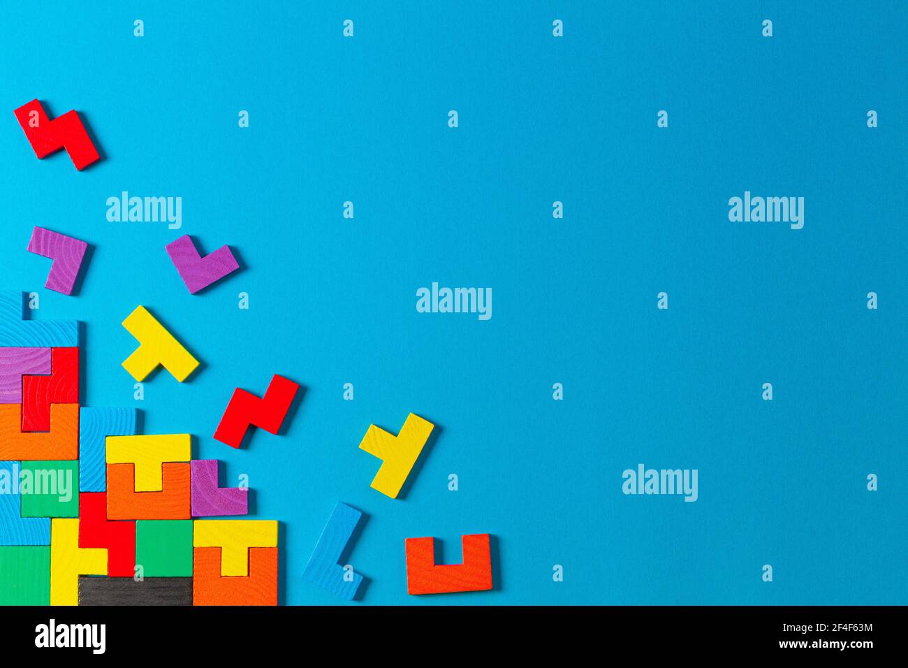 Different colorful shapes wooden puzzle blocks on light blue background ...