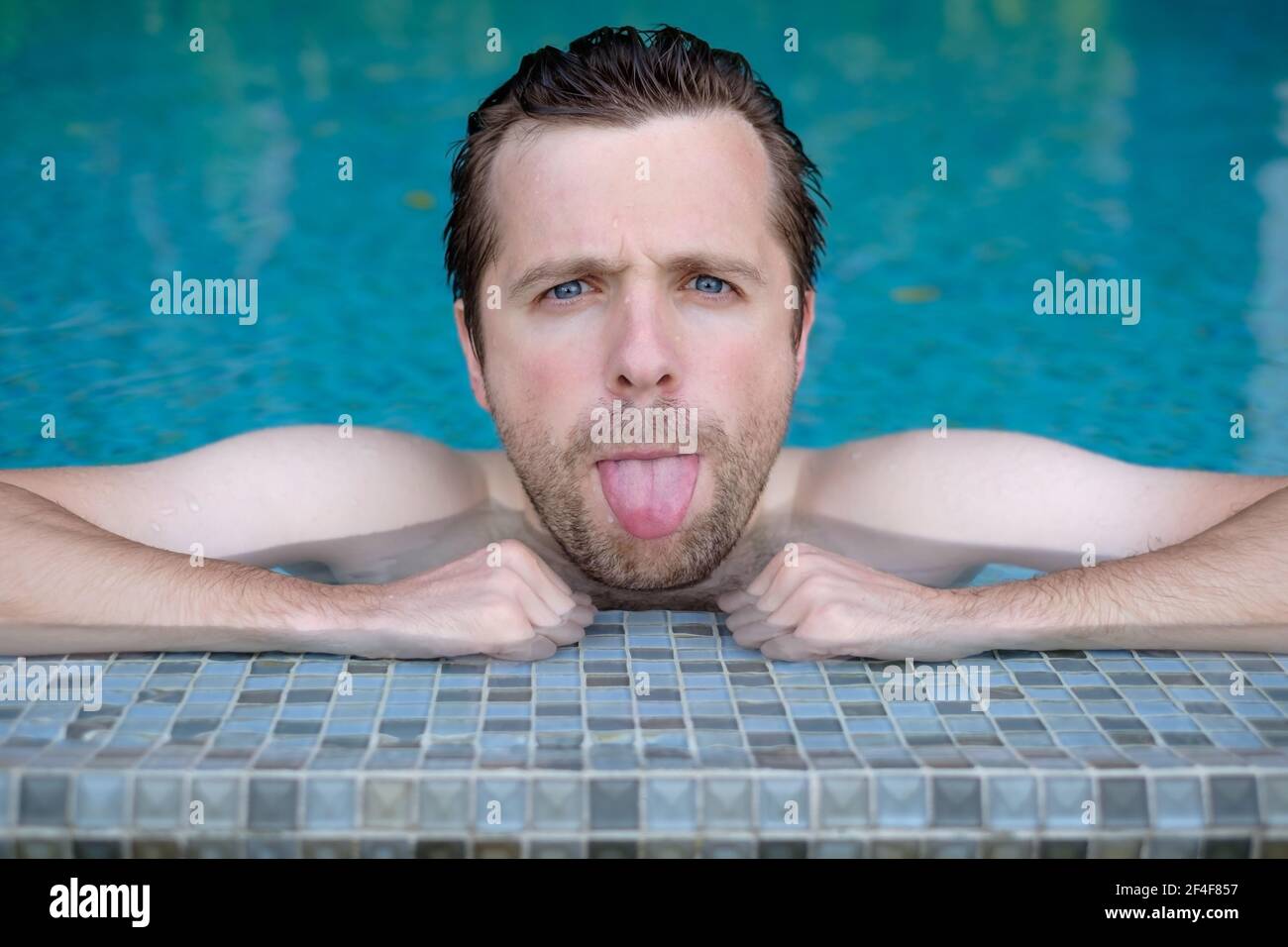 Portrait of a caucasian man putting out his tongue resting in the ...