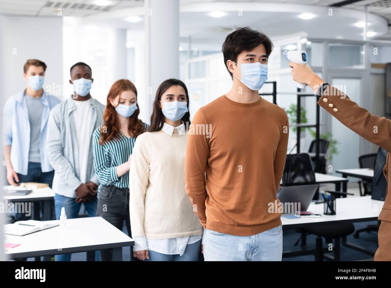 Person with contactless thermometer cheking diverse people temperature ...