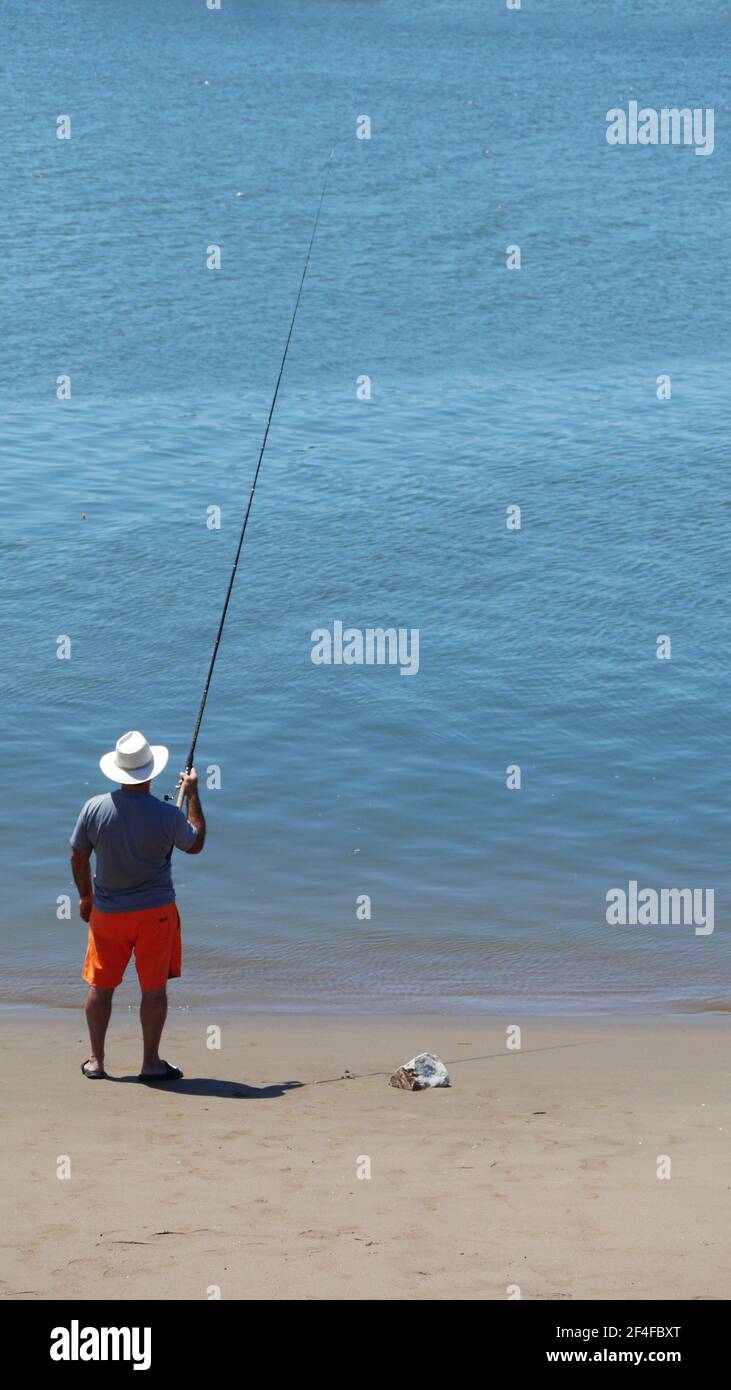 A back view of a fishing man on a beach Stock Photo - Alamy