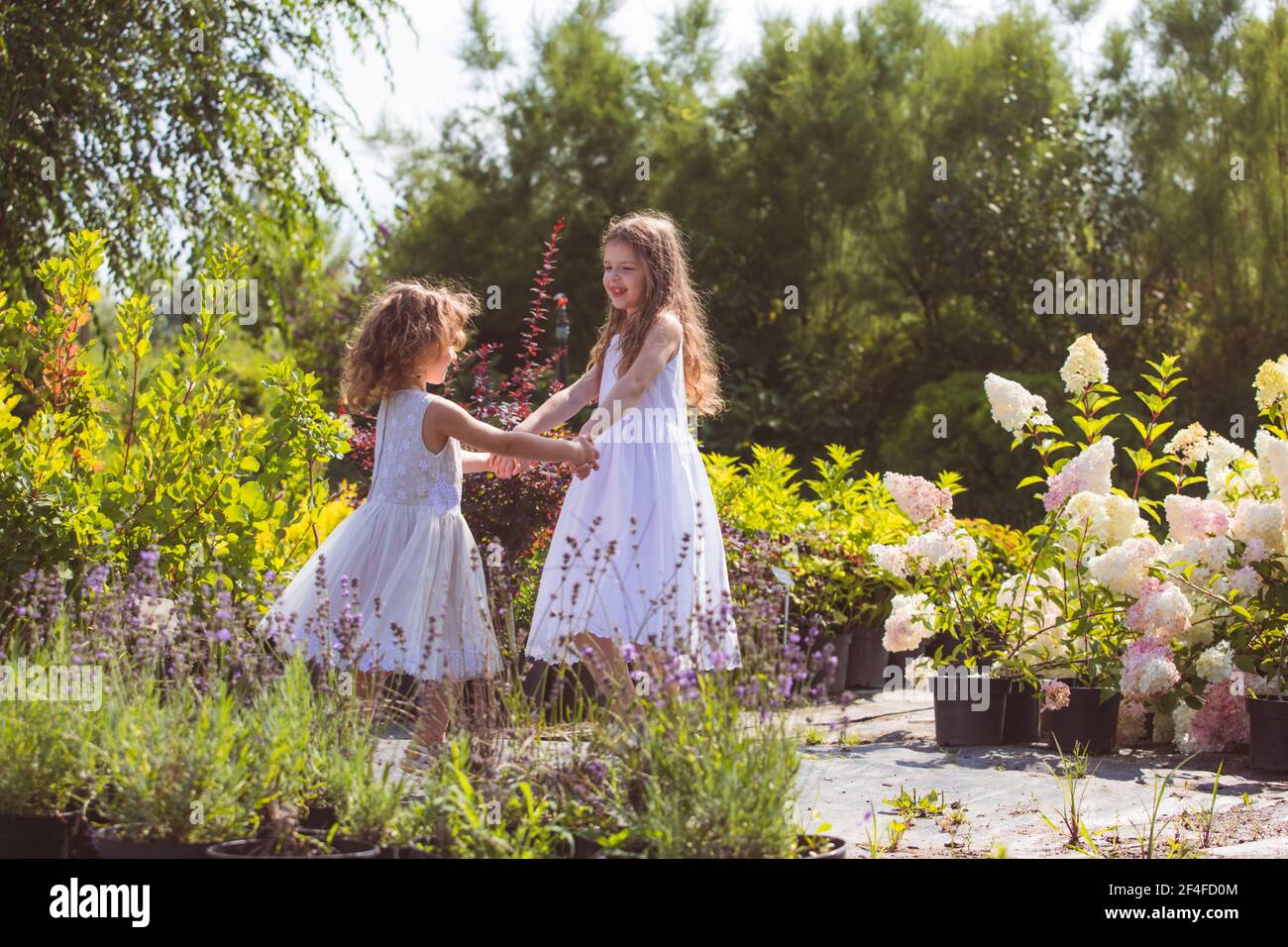 Little girls dancing among wonderful blooming flowers Stock Photo - Alamy