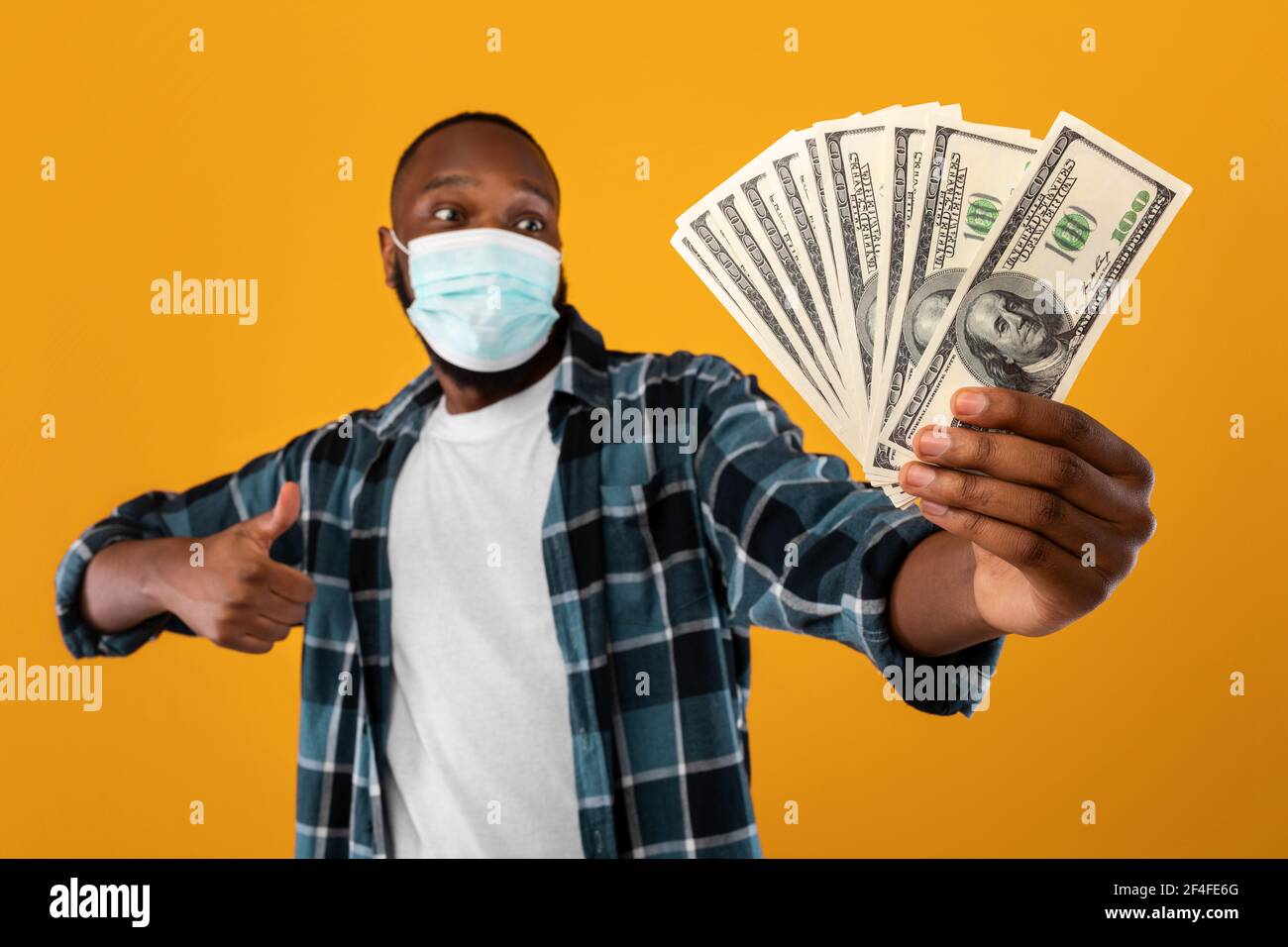 Black Man Holding Money And Gesturing Thumbs-Up On Yellow Background ...