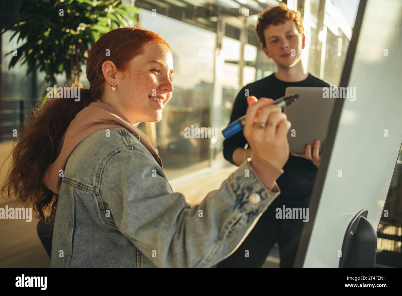 Student writing on whiteboard in classroom. Female student writing on ...