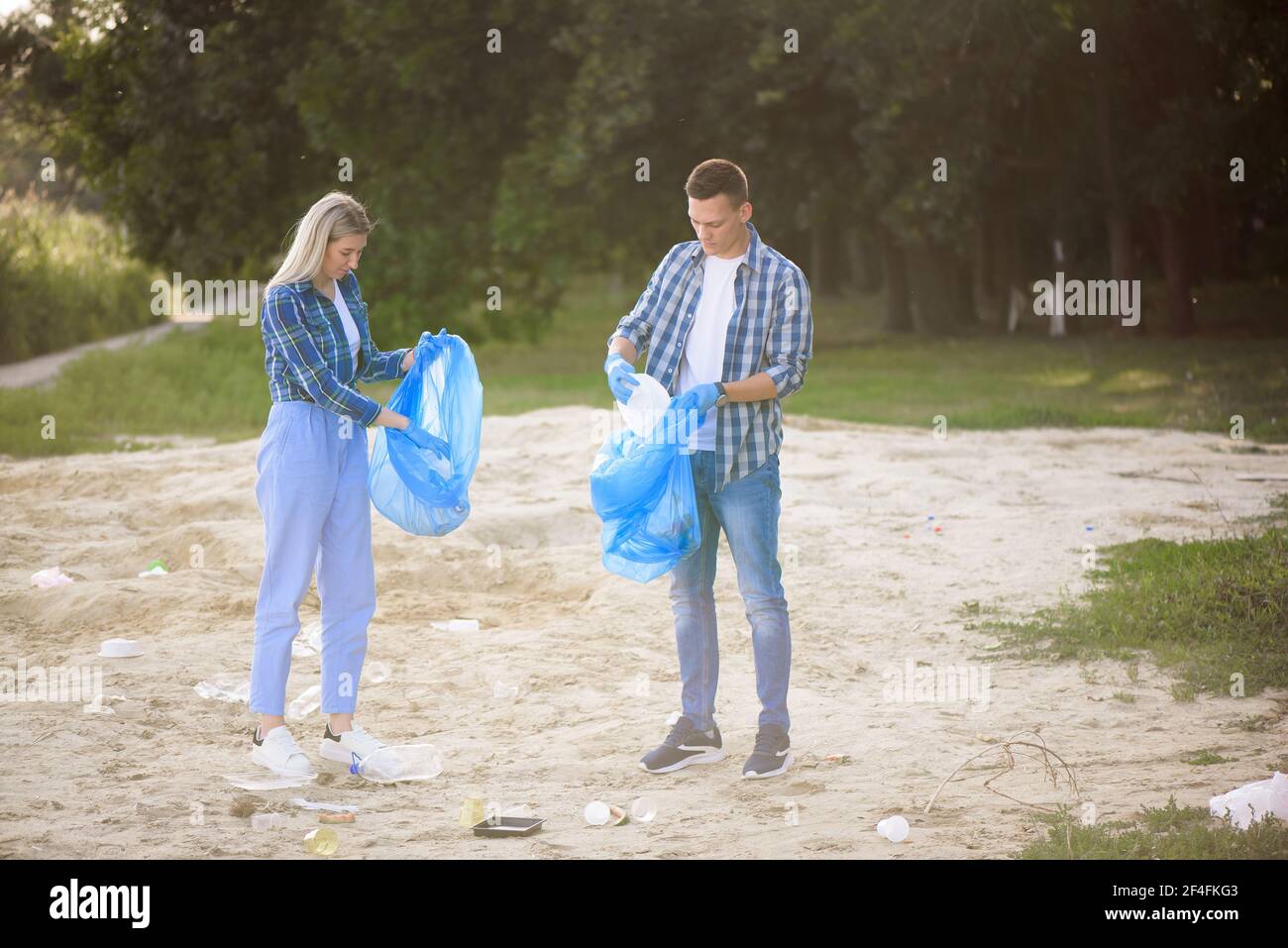 Young man and woman picking up trash outdoor Stock Photo - Alamy
