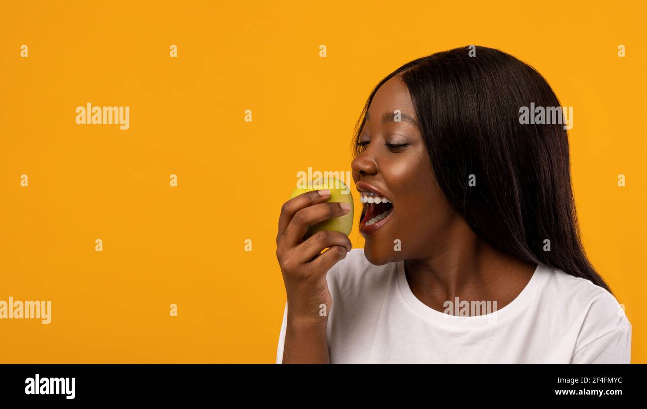 Healthy black lady eating green apple, panorama with copy space Stock ...