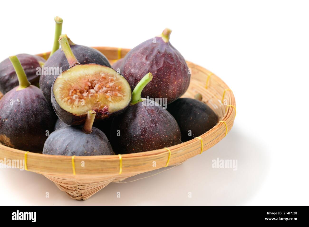 Fresh purple fig fruit and slices in bamboo basket isolated on white ...
