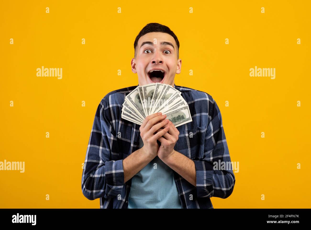 Excited Caucasian guy holding fan of money, screaming OMG on orange ...