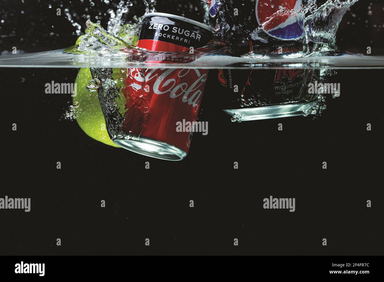 Close up view of two cans falling in water. Coca cola vs Pepsi cola ...