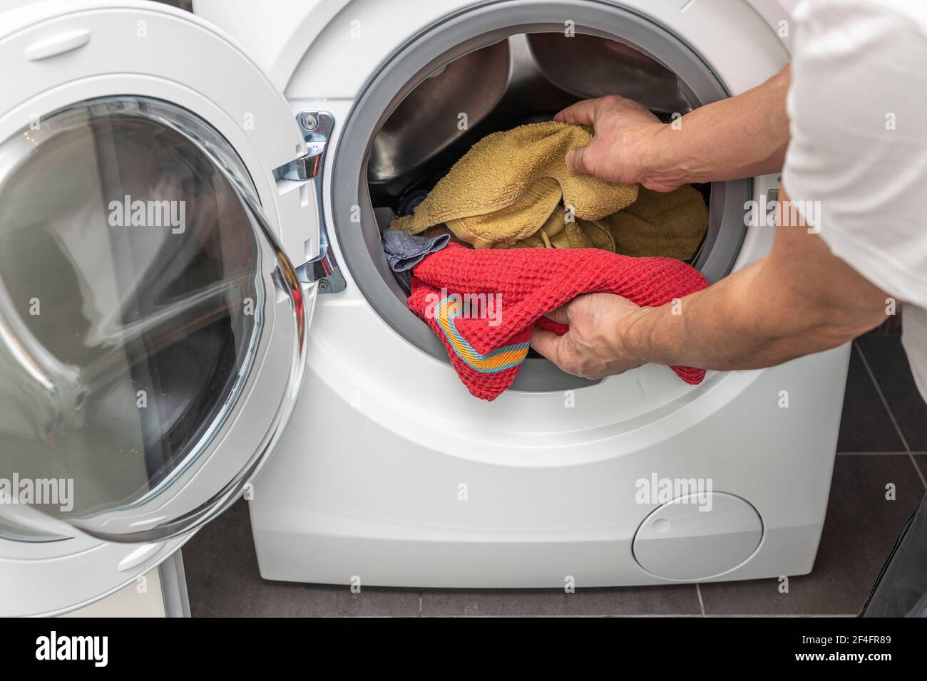 Close up view of man loading clothes to washing machine Stock Photo - Alamy