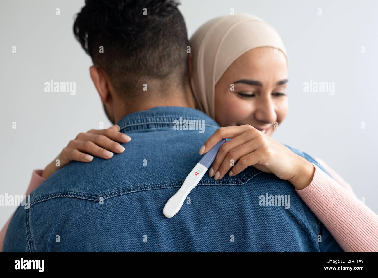 Emotional muslim woman with pregnancy test hugging husband, closeup ...