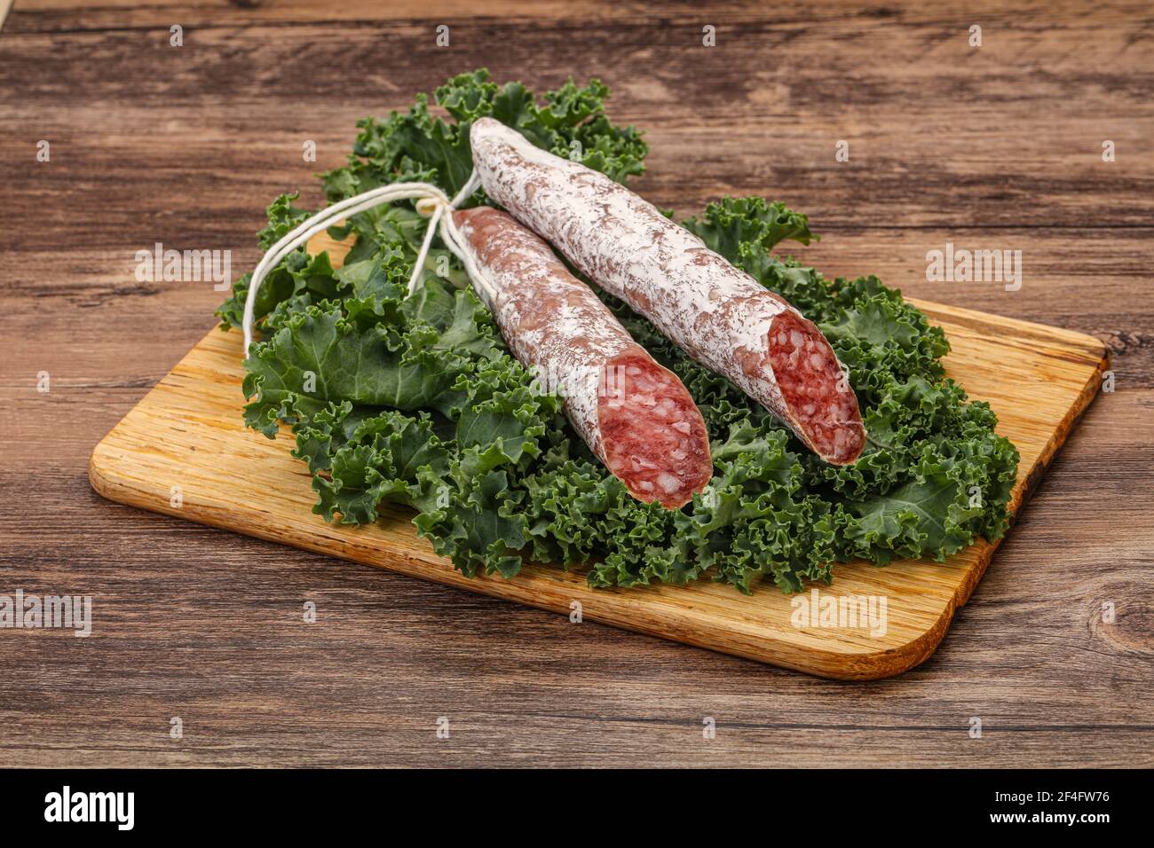 Spanish Fuet sausage with salad leaves over wooden background Stock ...