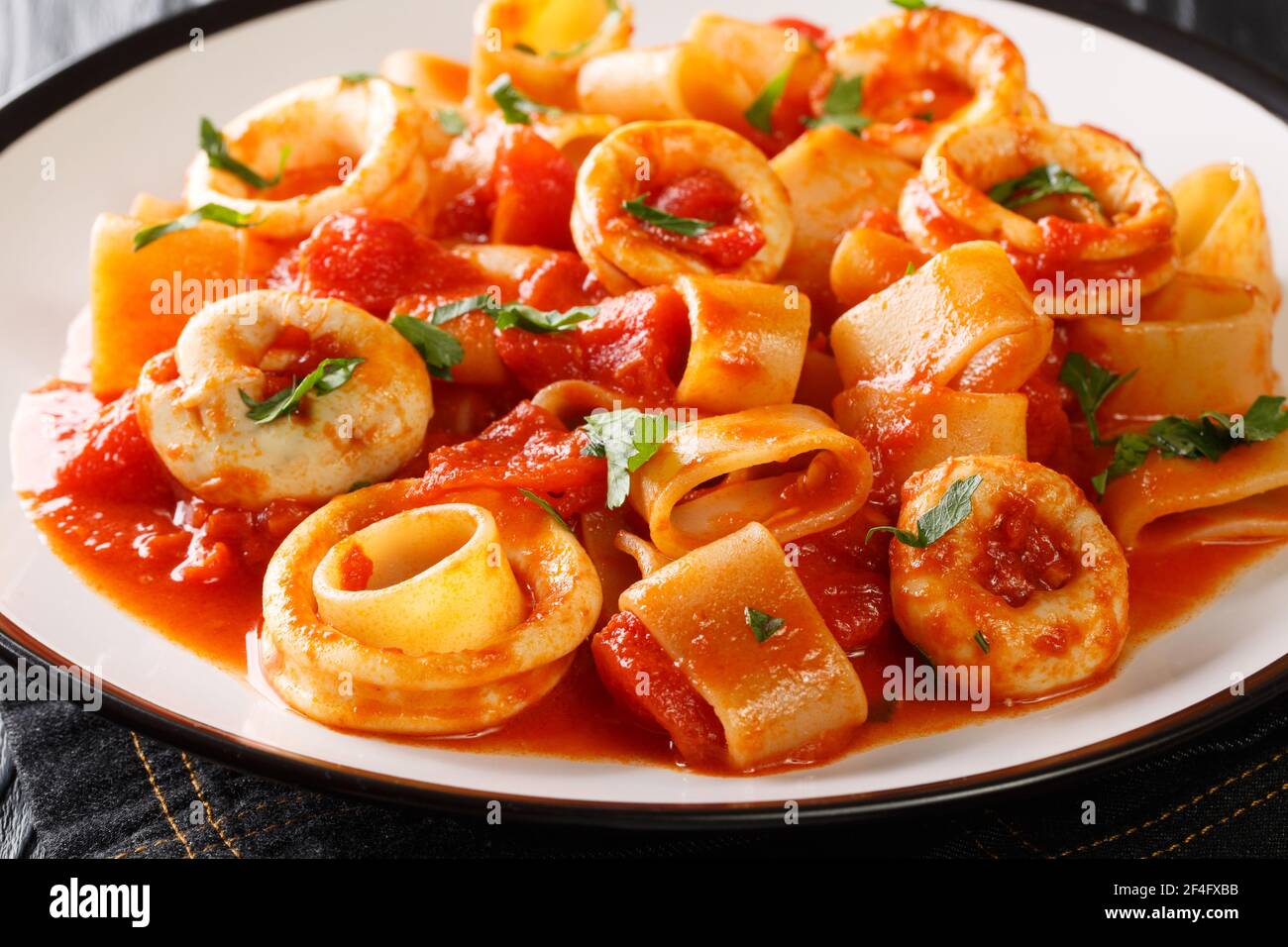 Italian Calamarata Pasta with calamari and tomato sauce close-up in a ...