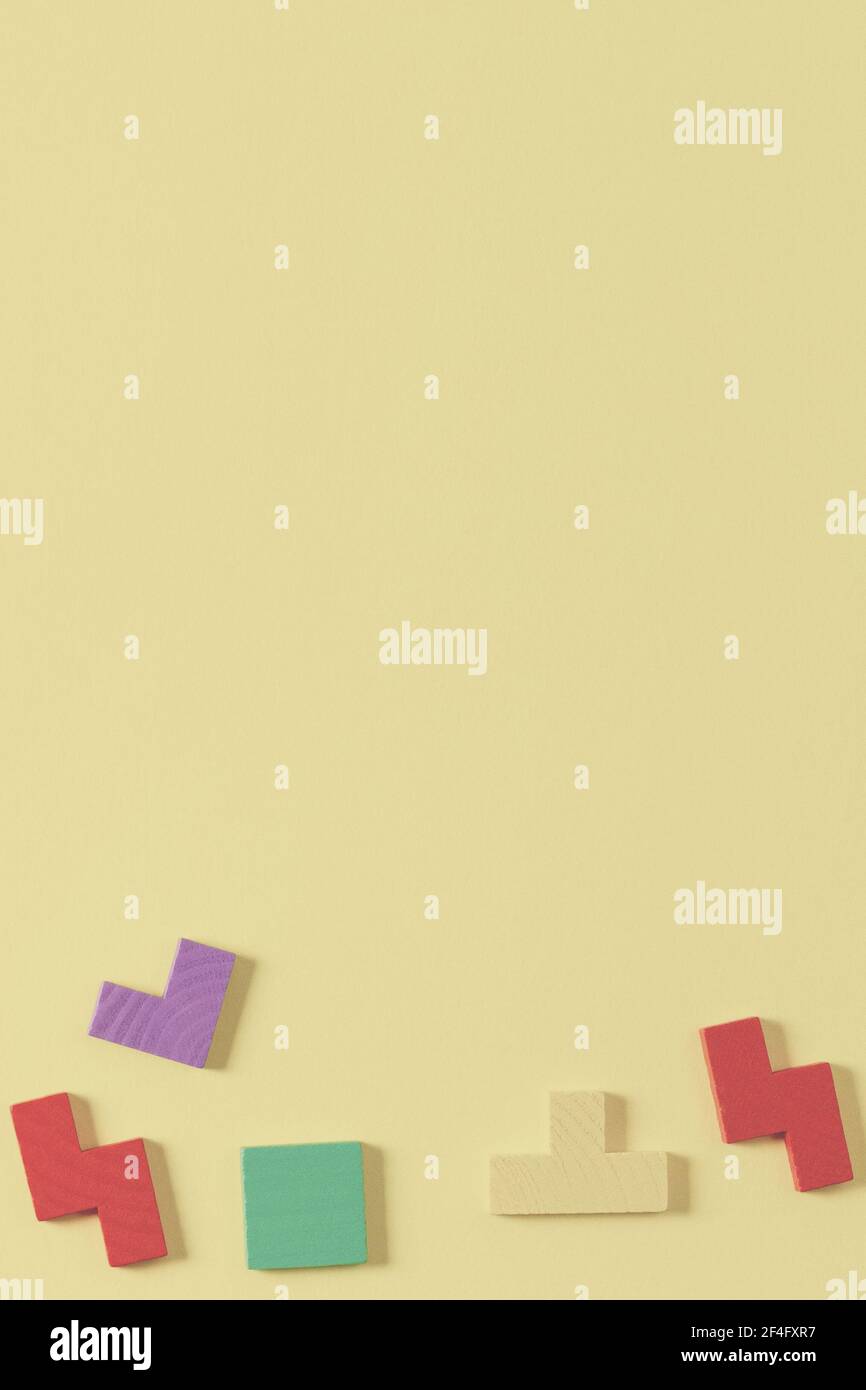 Different colorful shapes wooden puzzle blocks on yellow background ...