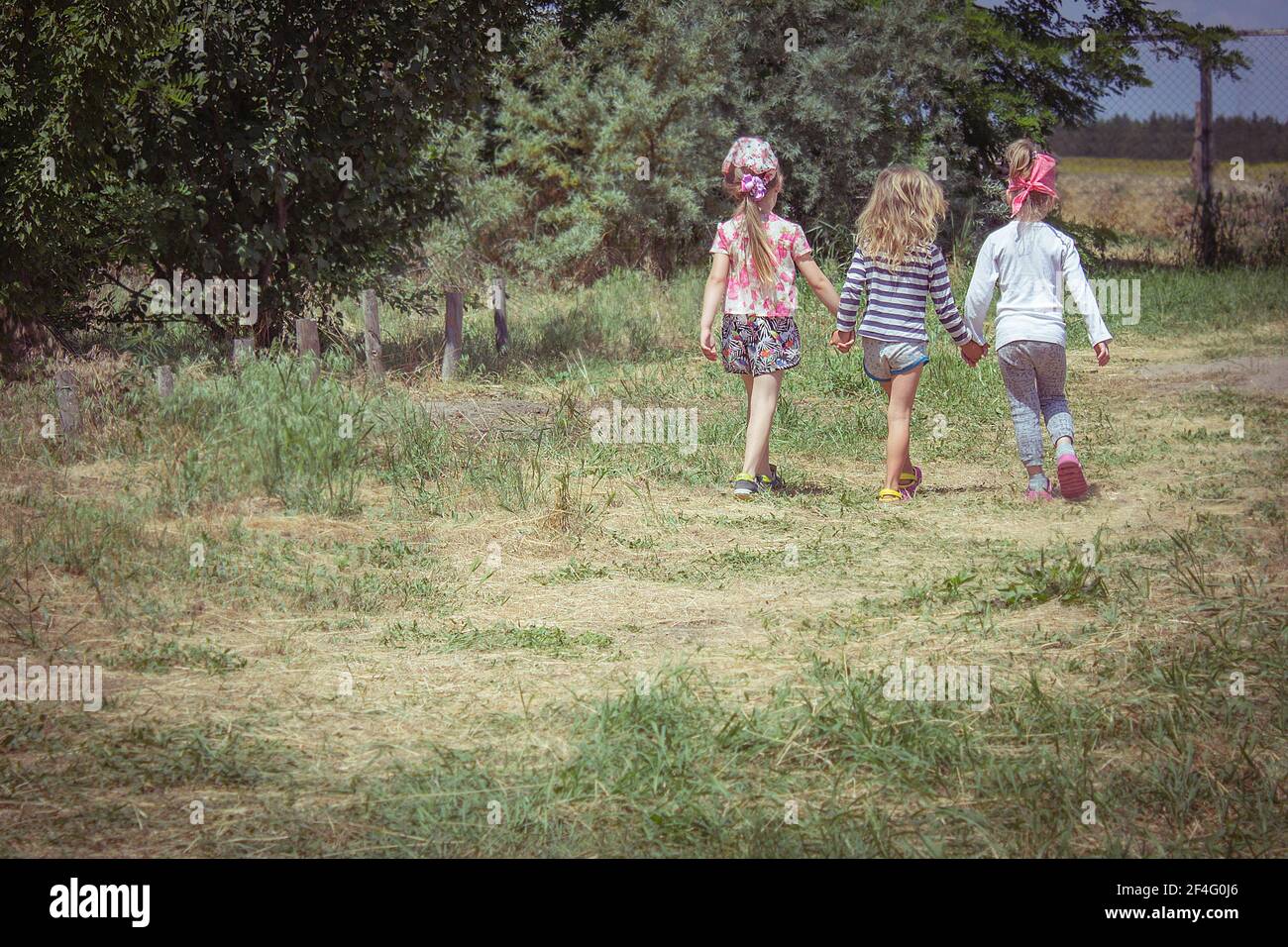 Three little girls walking outdoors holding hands. Girlfriends or ...