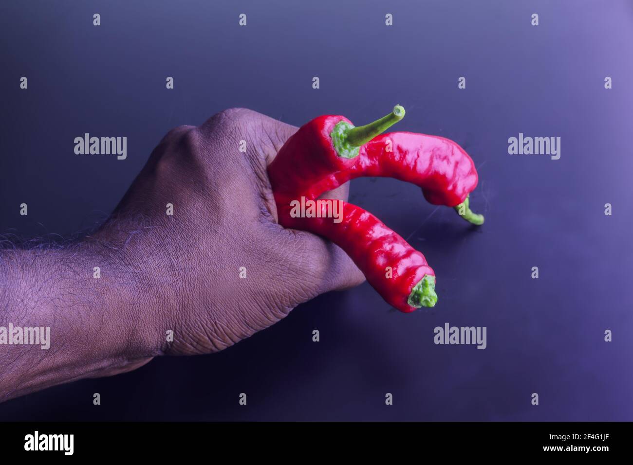 A top view of a strong male hand holding red hot chili peppers on the ...