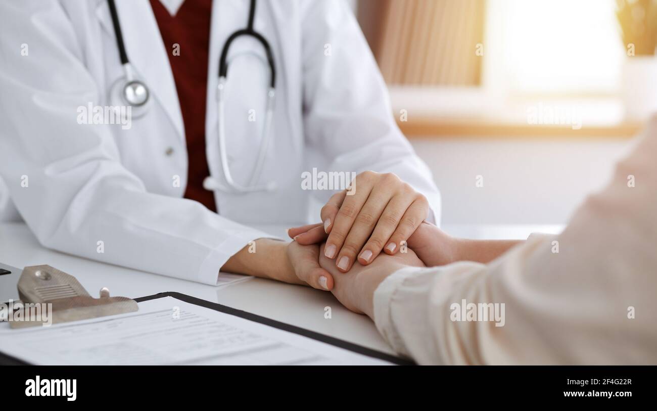 Hands of unknown woman-doctor reassuring her female patient in sunny ...