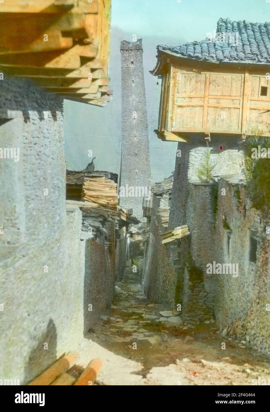 View down a narrow village path on a sunny day, with wooden and stone ...