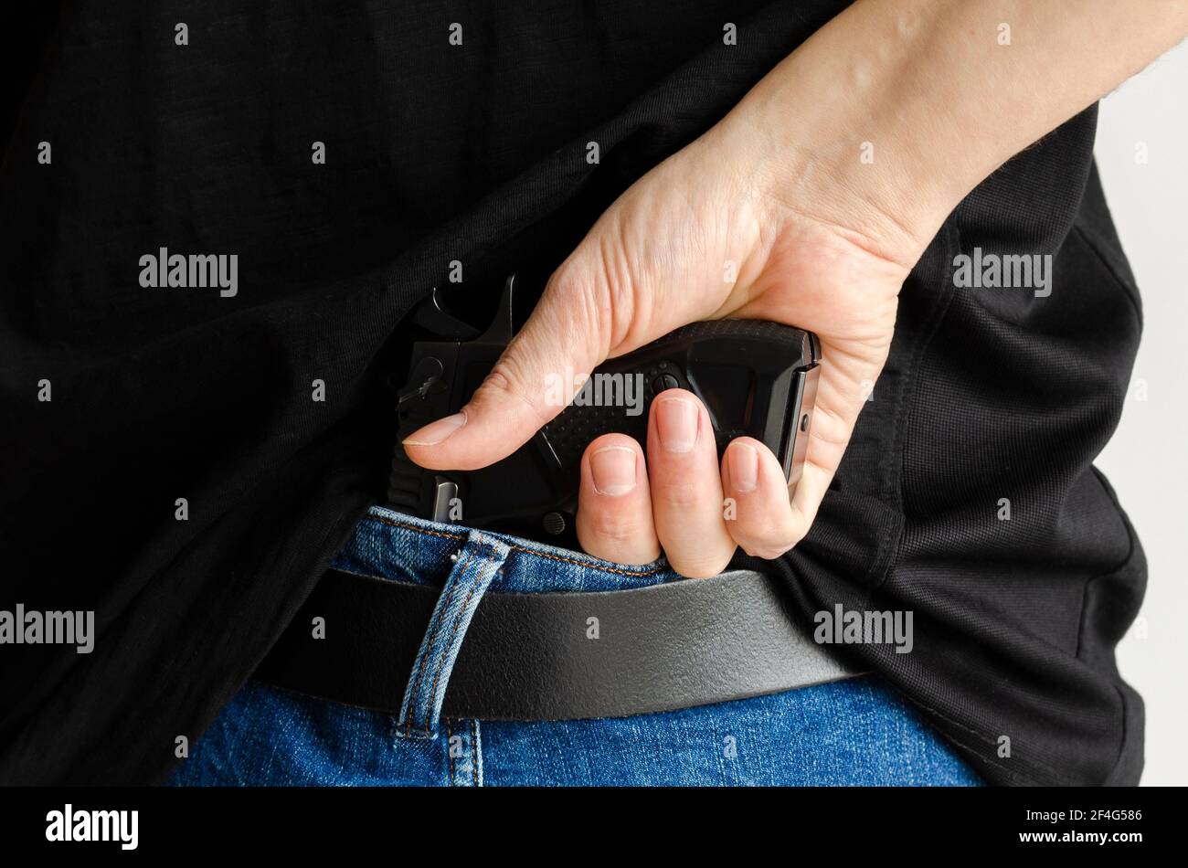 Hided handgun under the denim belt. a man in jeans and a t-shirt holds ...