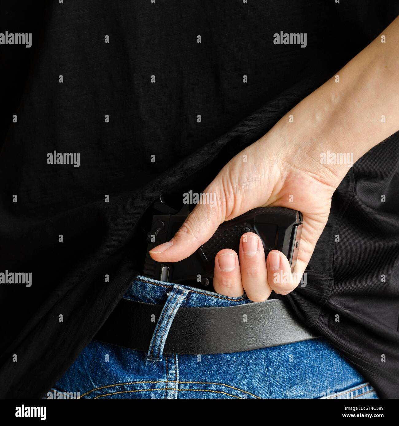 Hided handgun under the denim belt. a man in jeans and a t-shirt holds ...