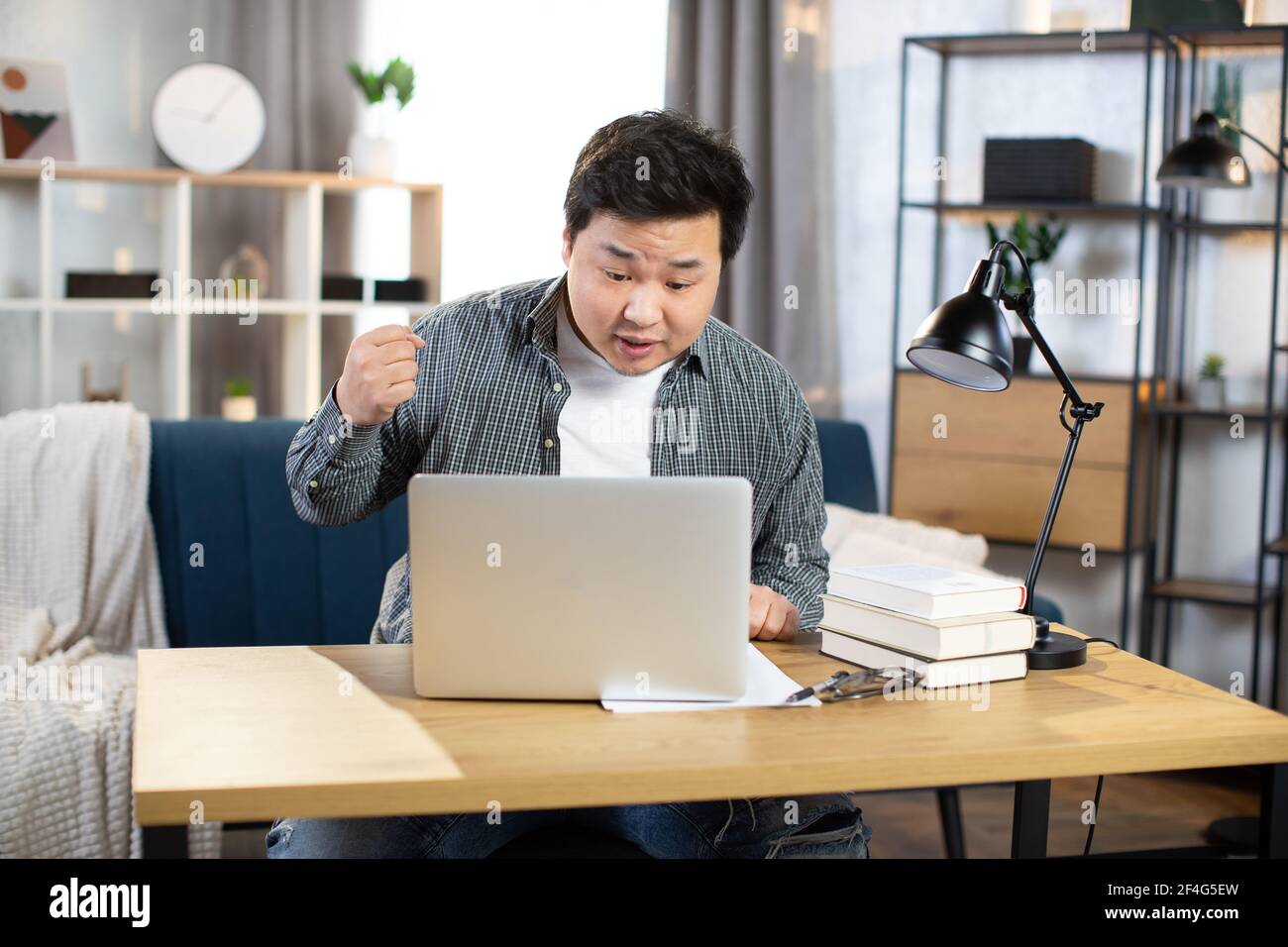Asian young man looking at computer screen and expressing happy ...