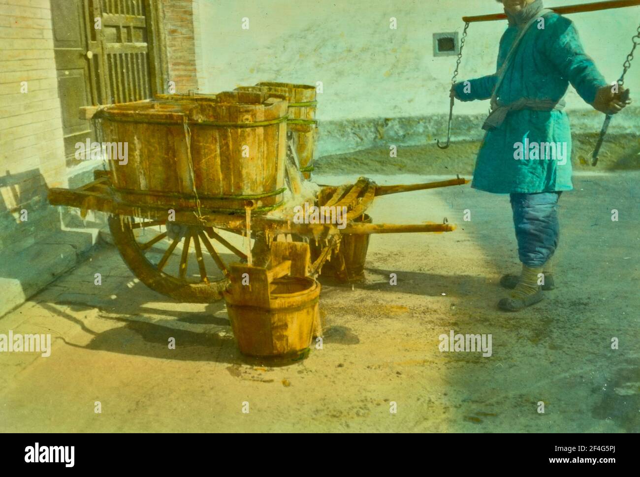 A man, with his face above the frame, stands near a wooden cart laden ...