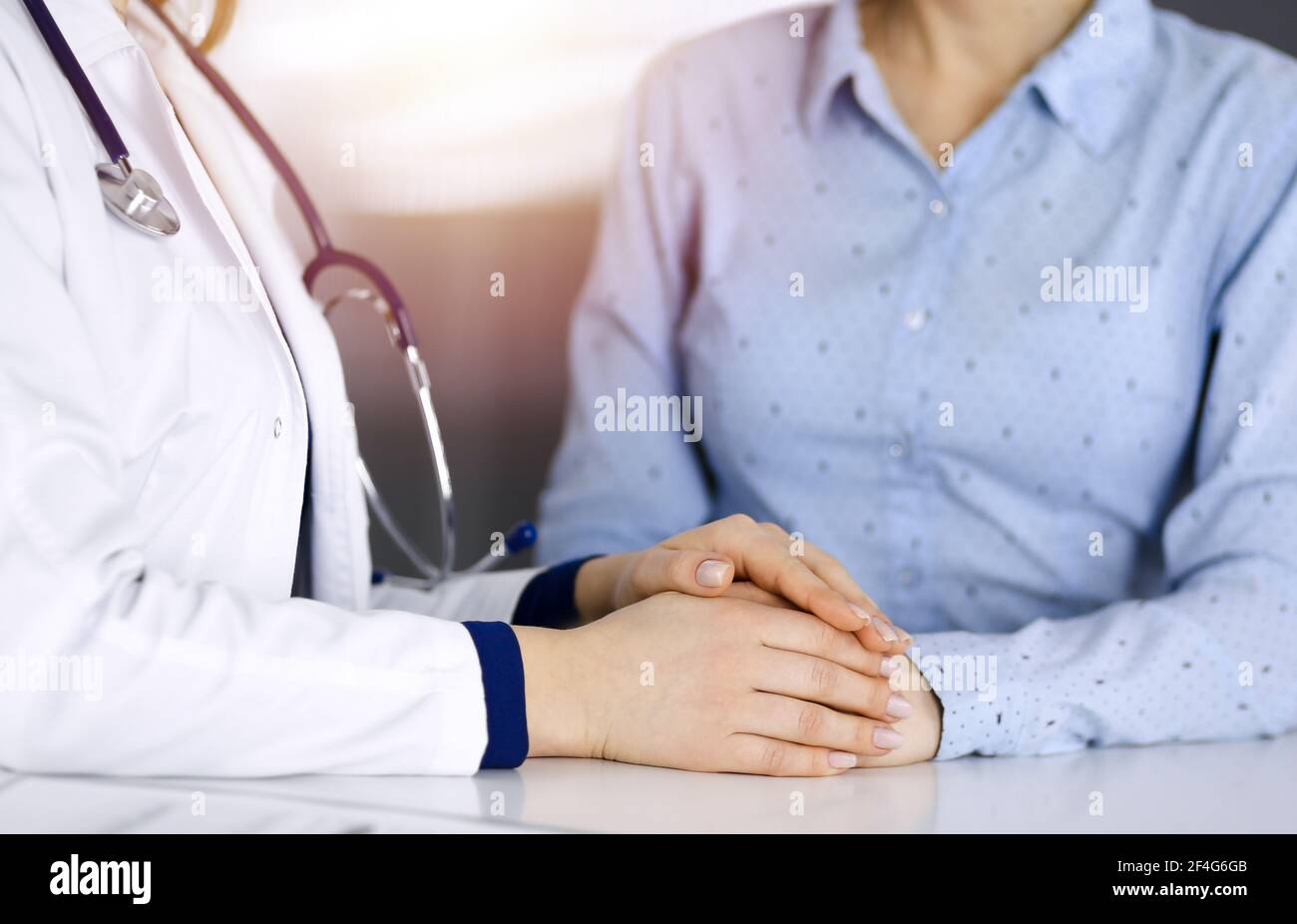 Unknown woman-doctor is holding her patient's hands to reassure a ...