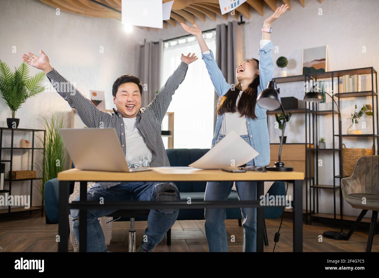Cheerful asian young man and woman, throwing papers around after ...