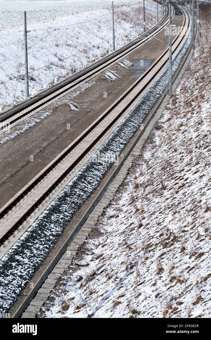 an electrified railway line in winter with snowy slopes alongside the ...