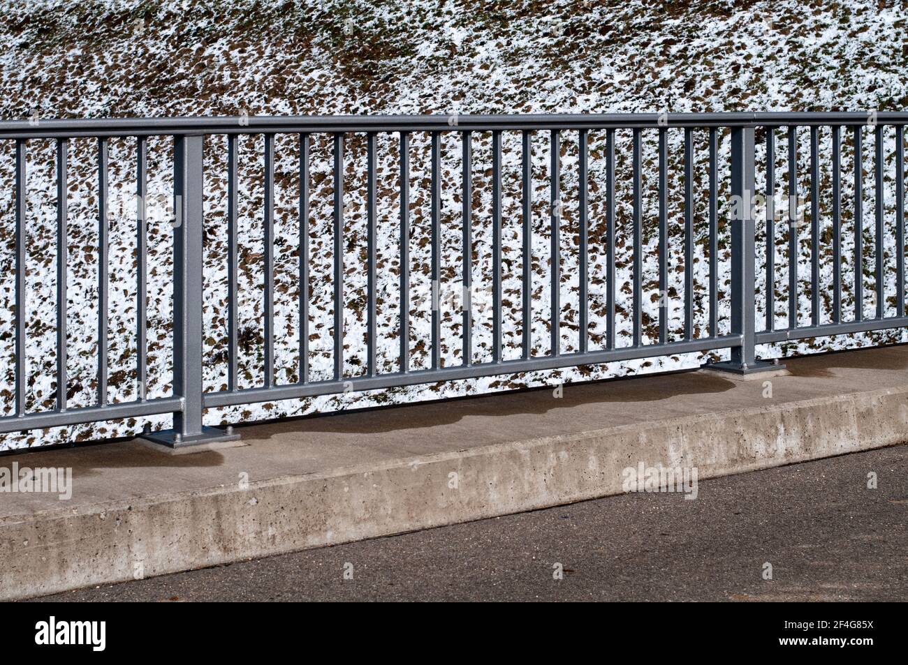 the simple metal railing of a bridge over railway tracks with a snowy ...