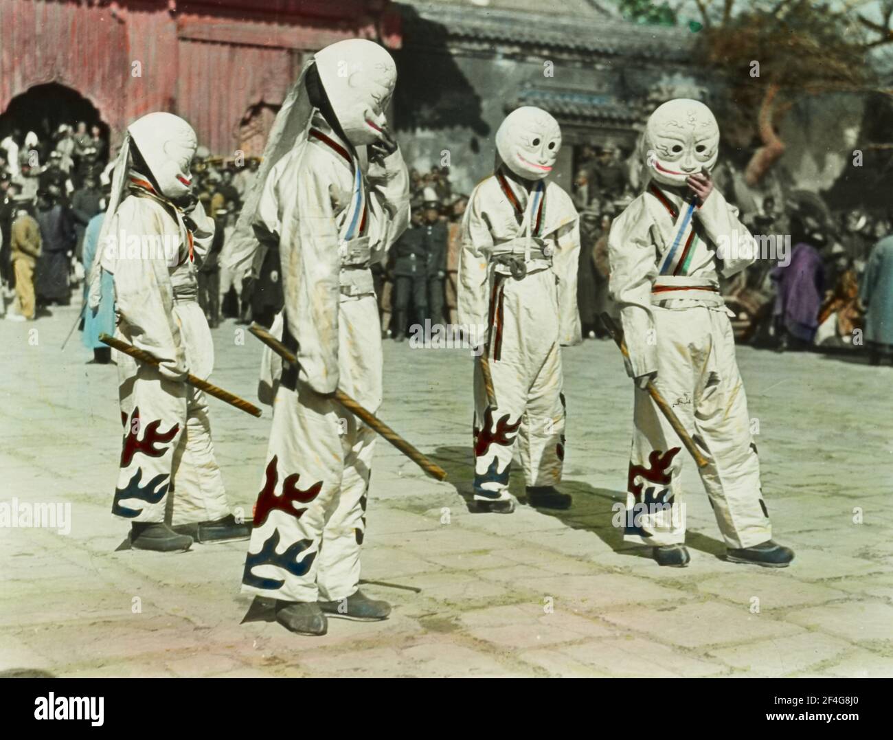 Full-length view of four masked performers, each holding a stick ...