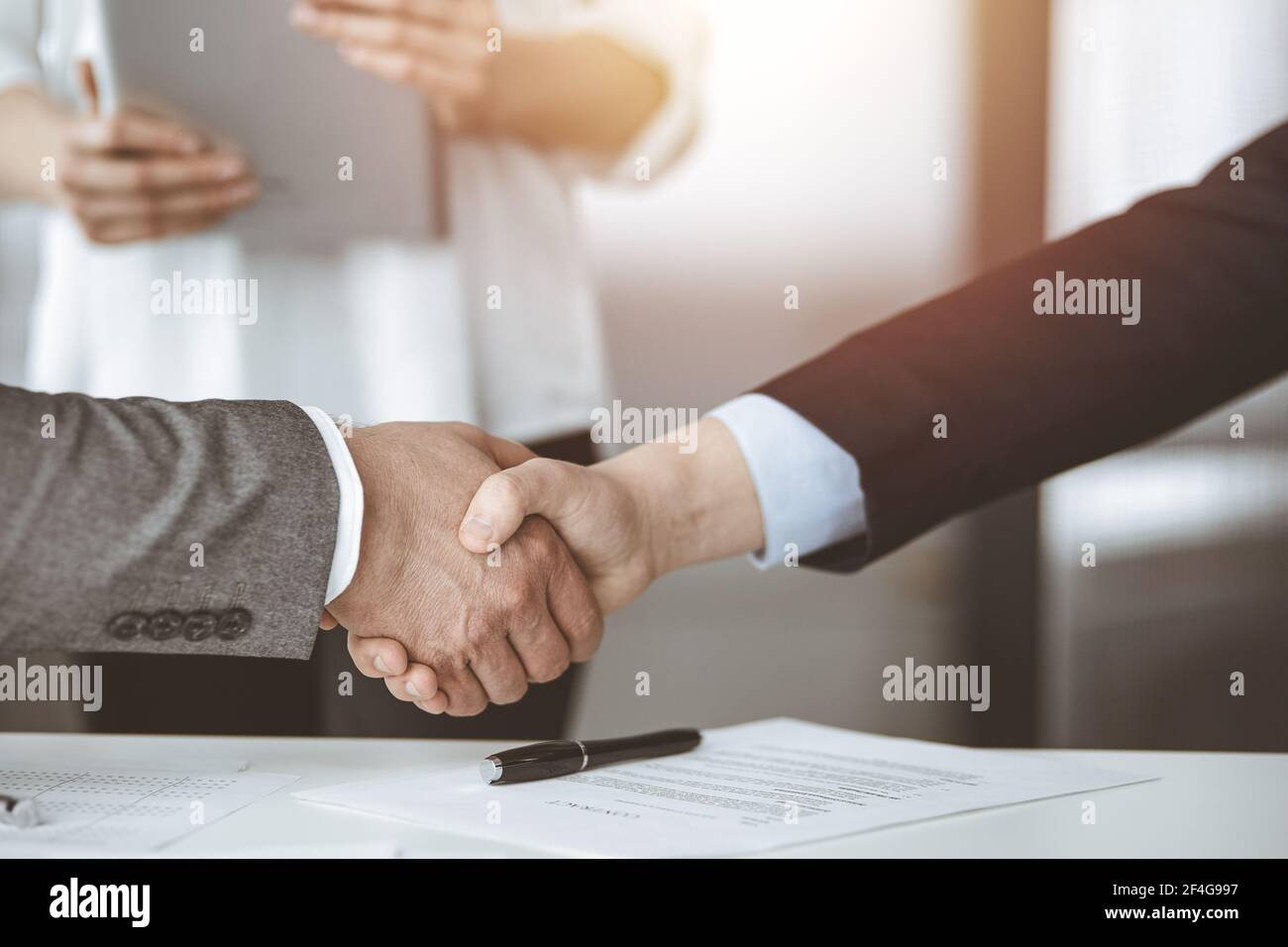 Business people shaking hands finishing contract signing in sunny ...