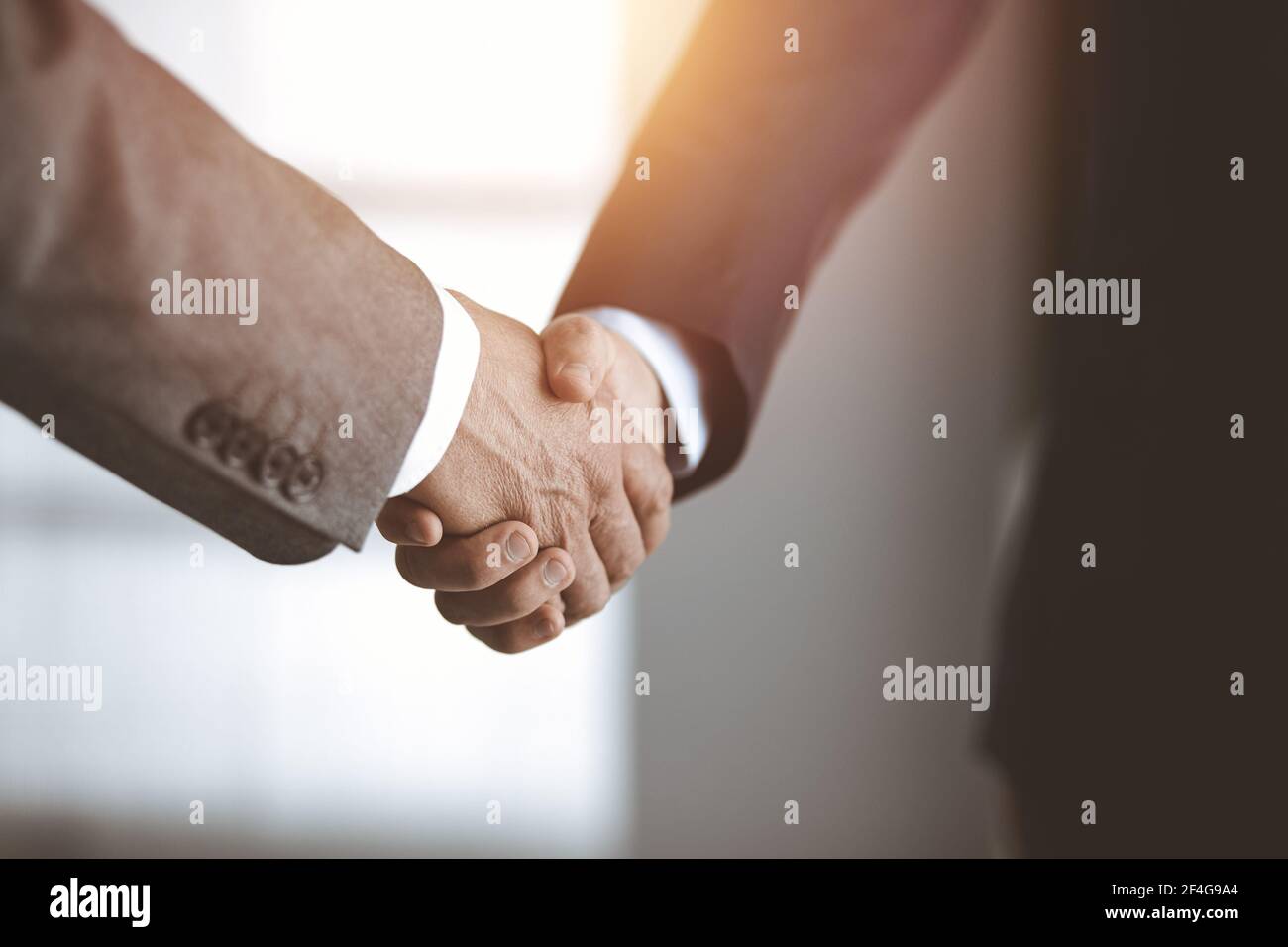 Business people standing and shaking hands in sunny office, close-up ...