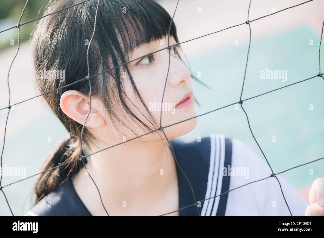 Portrait of beautiful Asian japanese high school girl uniform looking with net in green ...