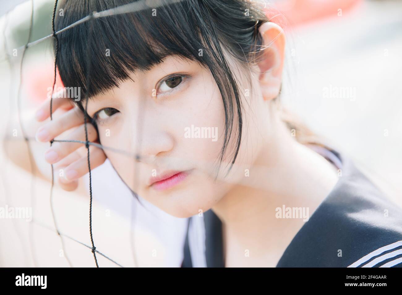 Portrait of beautiful Asian japanese high school girl uniform looking with net in green ...