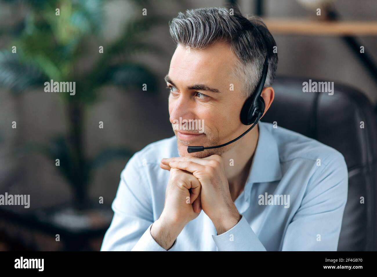 A handsome mature grey-haired call center employee, freelancer, in the ...