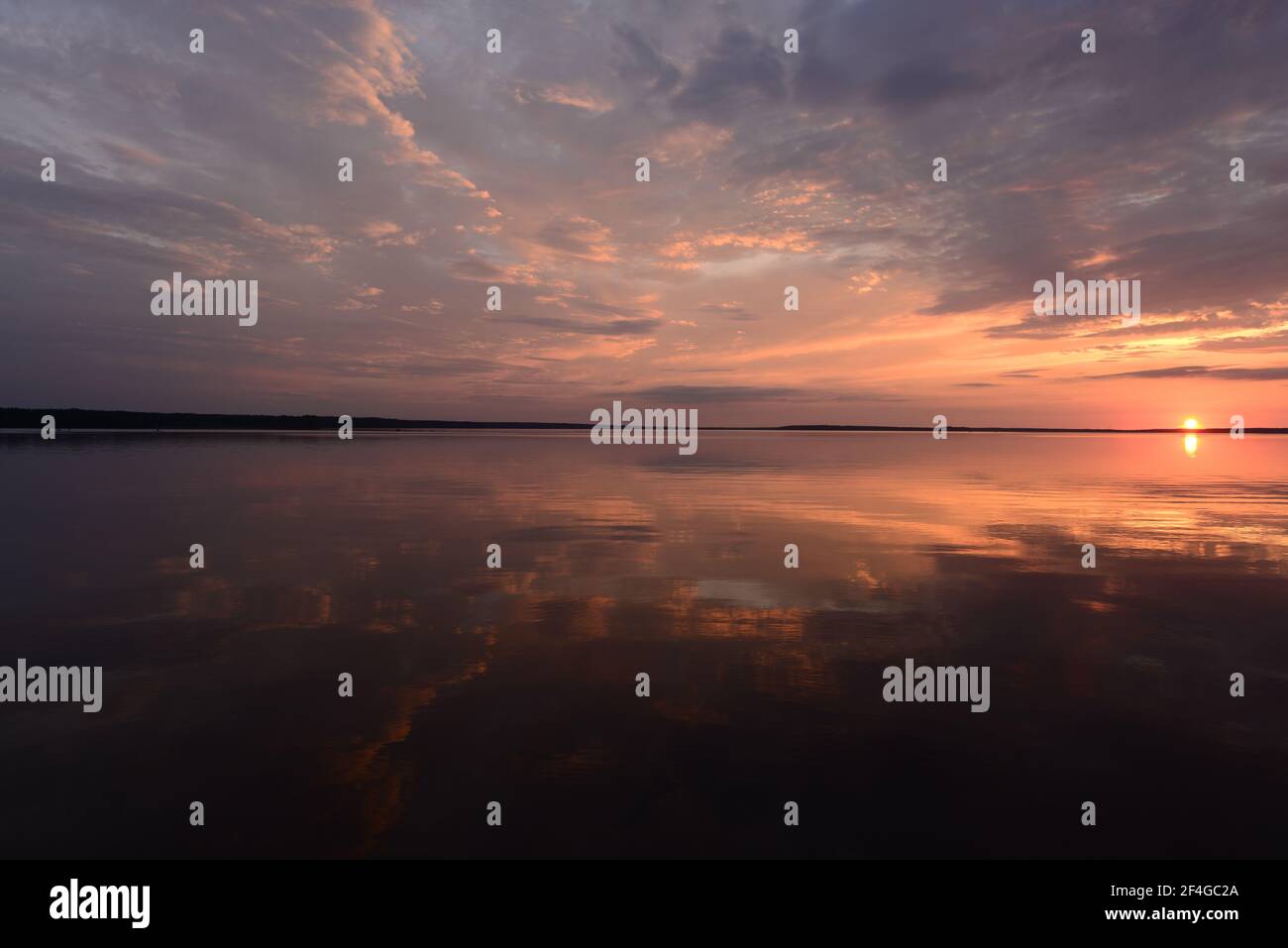 sun setting on the horizon above the water surface lake Stock Photo - Alamy