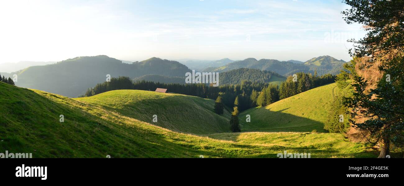 swiss hill landscape at sunset. The last rays of sun light up the ...