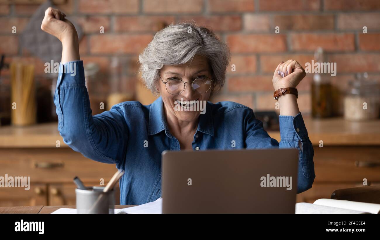 Excited mature lady scream achieving success in learning computer app ...